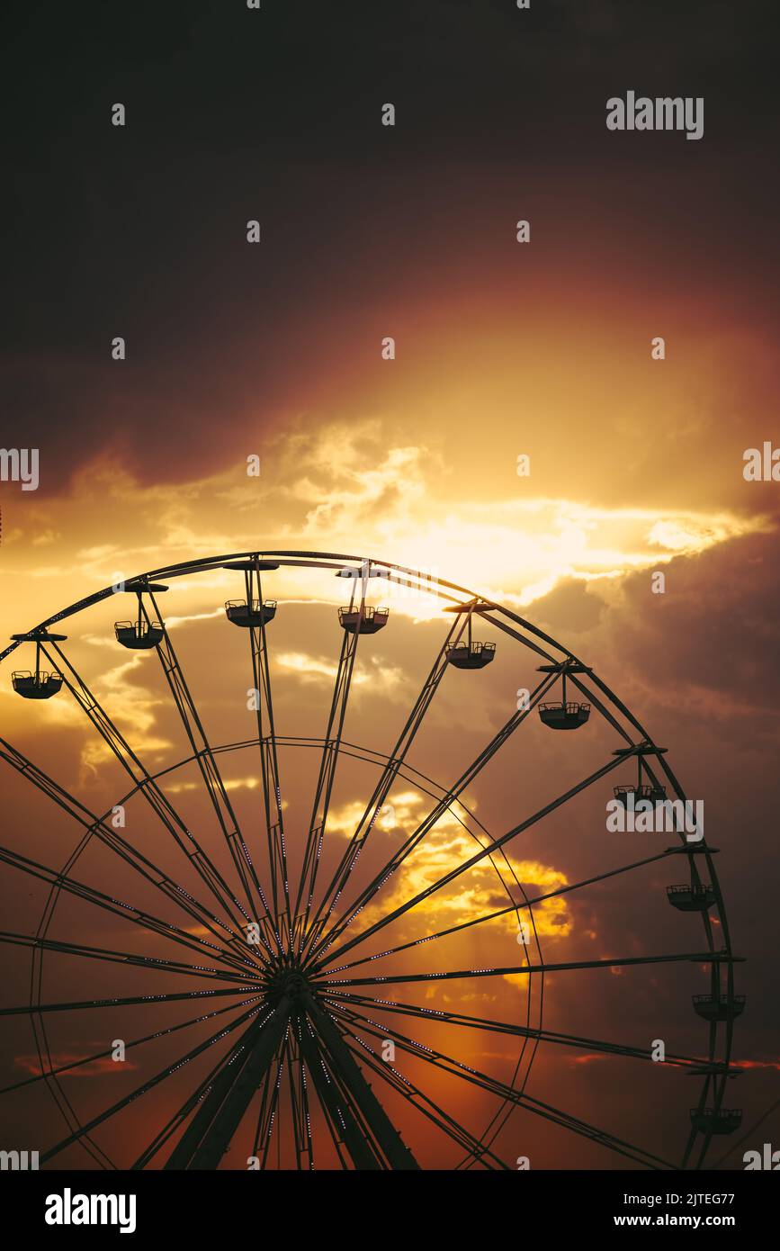 Ferris Wheel in amusement park and scenic sunset clouds in sky and ...