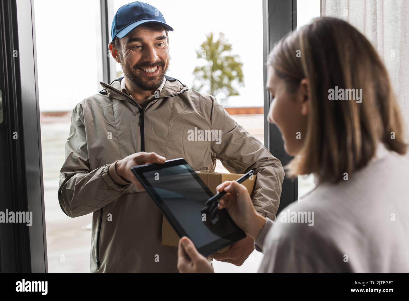 delivery man with box and woman signs digital form Stock Photo - Alamy