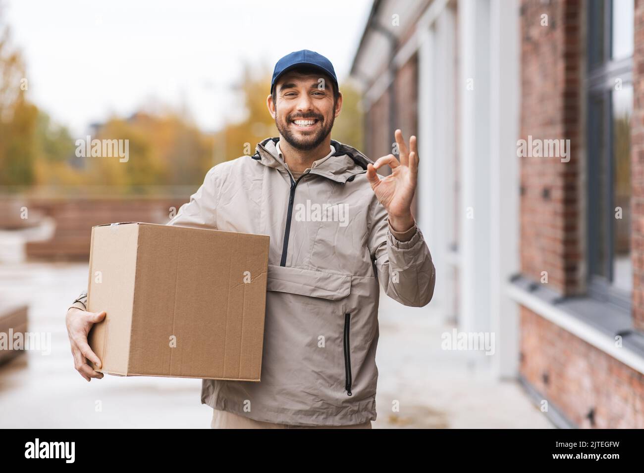 smiling delivery man with parcel box showing ok Stock Photo - Alamy