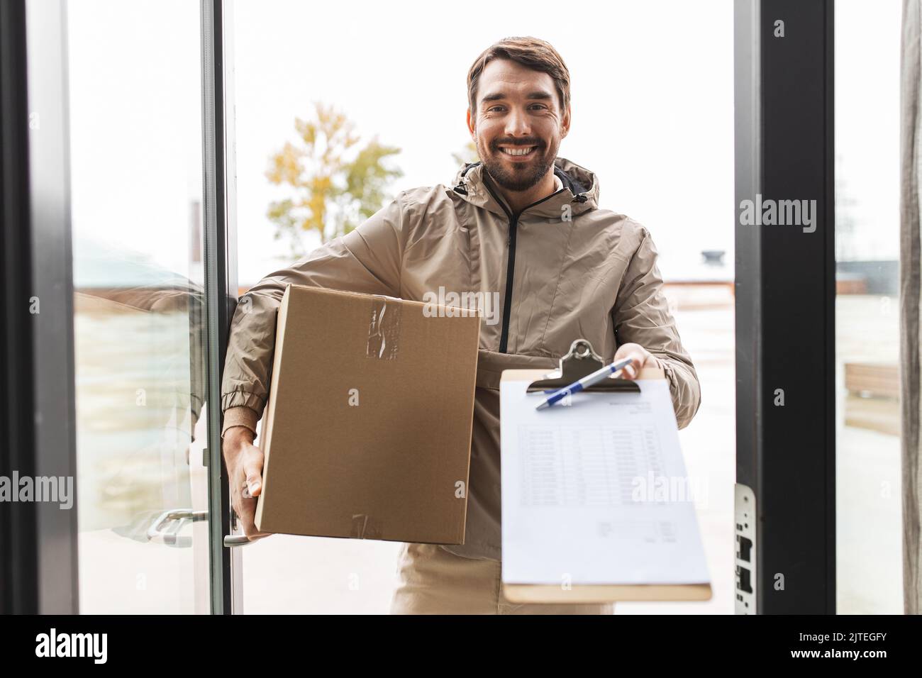 smiling delivery man with parcel box at open door Stock Photo - Alamy