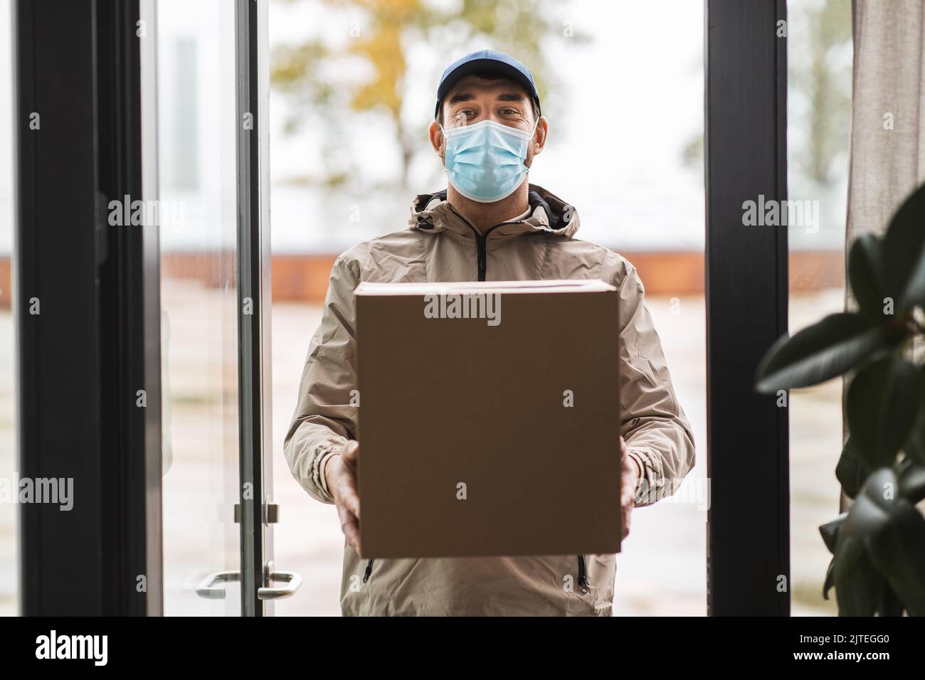 delivery man in face mask holding parcel box Stock Photo - Alamy