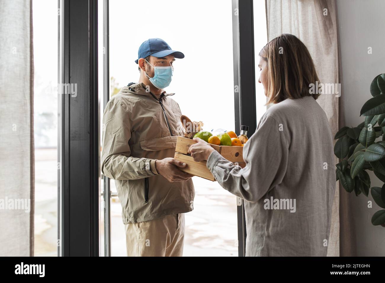 food delivery man in mask giving order to customer Stock Photo - Alamy