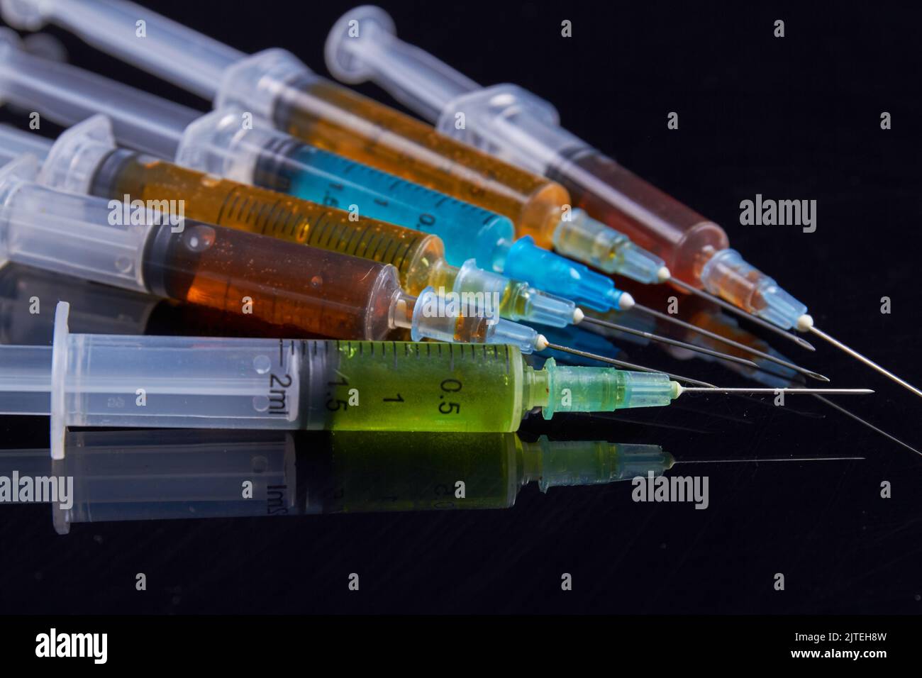 Close-up pile of syringes with colored drugs for injection. Isolated on ...