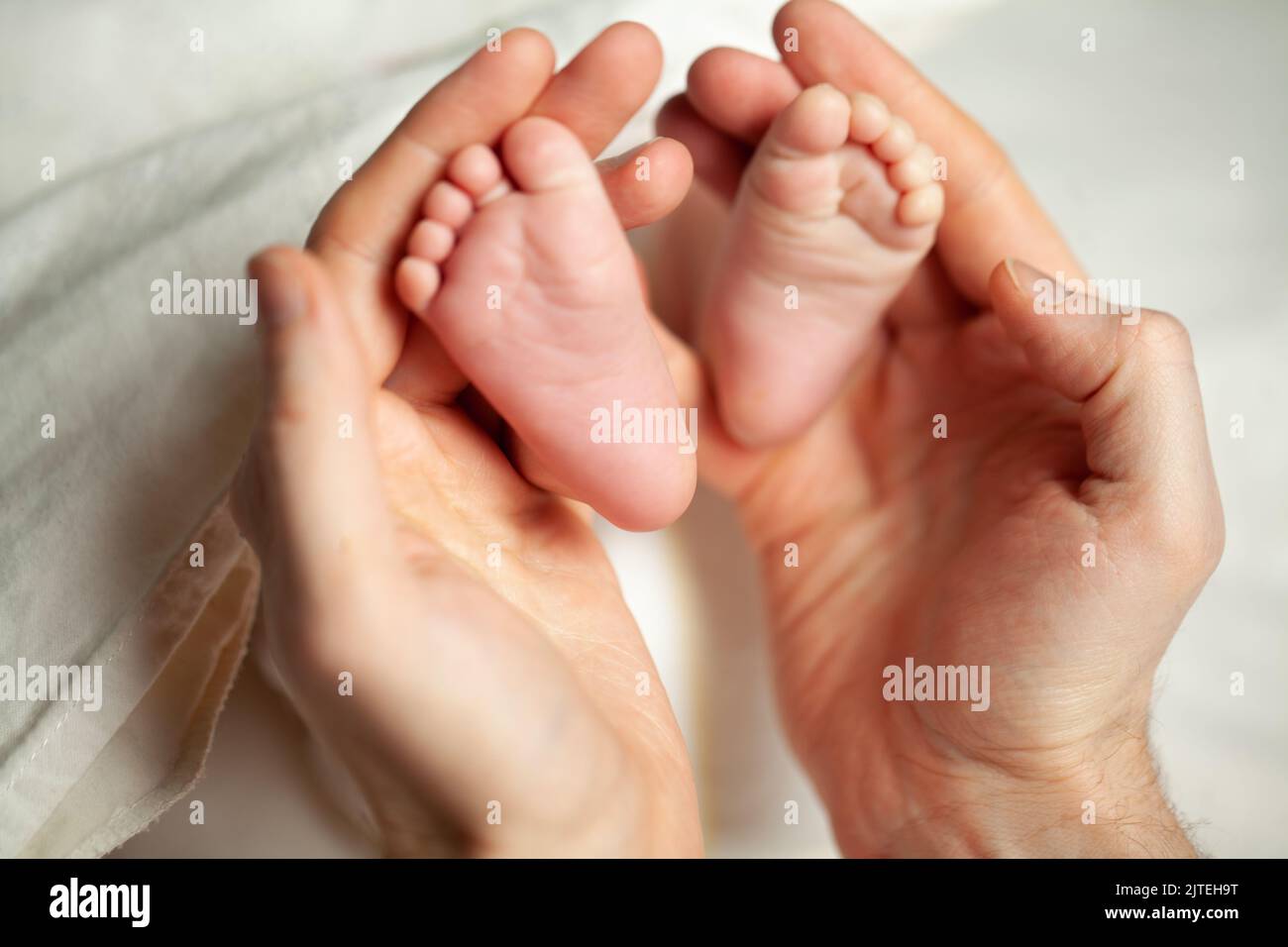 The feet of the baby in men's palms closeup Stock Photo - Alamy