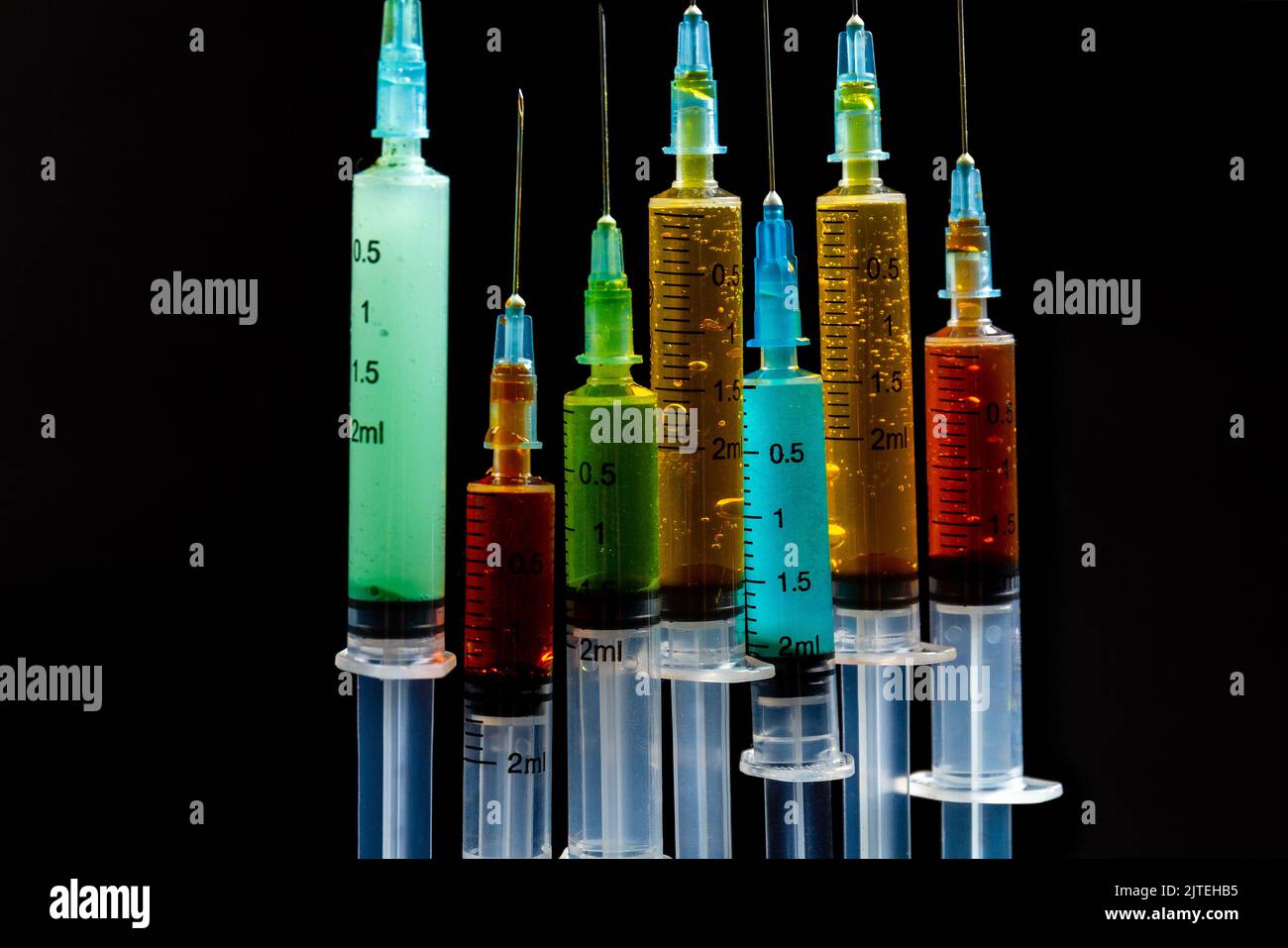 Close-up syringes with colorful medicine isolated on black background ...