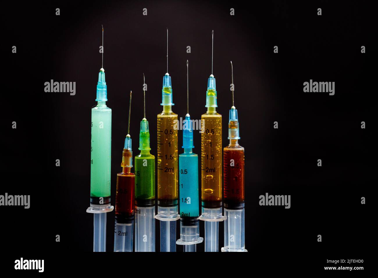 Vertical syringes with colored drug liquids on grey background ...