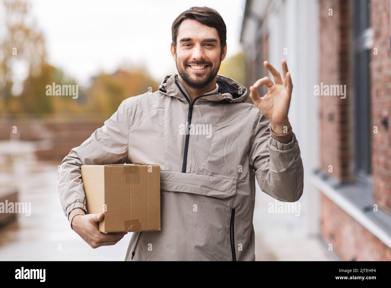 smiling delivery man with parcel box showing ok Stock Photo - Alamy