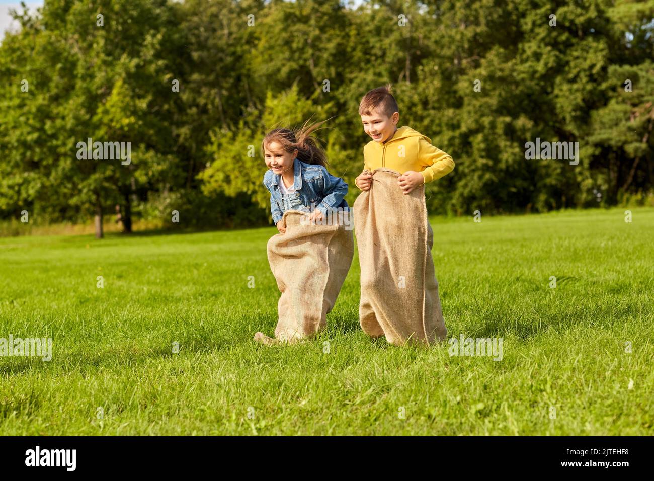 happy children playing bag jumping game at park Stock Photo - Alamy