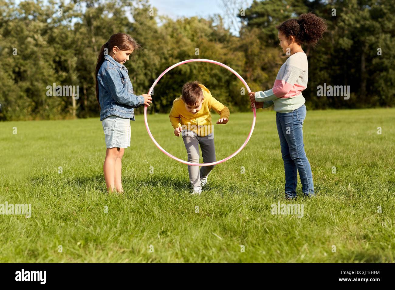 happy children jumping through hula hoop at park Stock Photo - Alamy