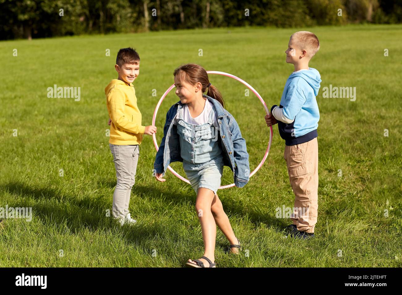 happy children playing game with hula hoop at park Stock Photo - Alamy