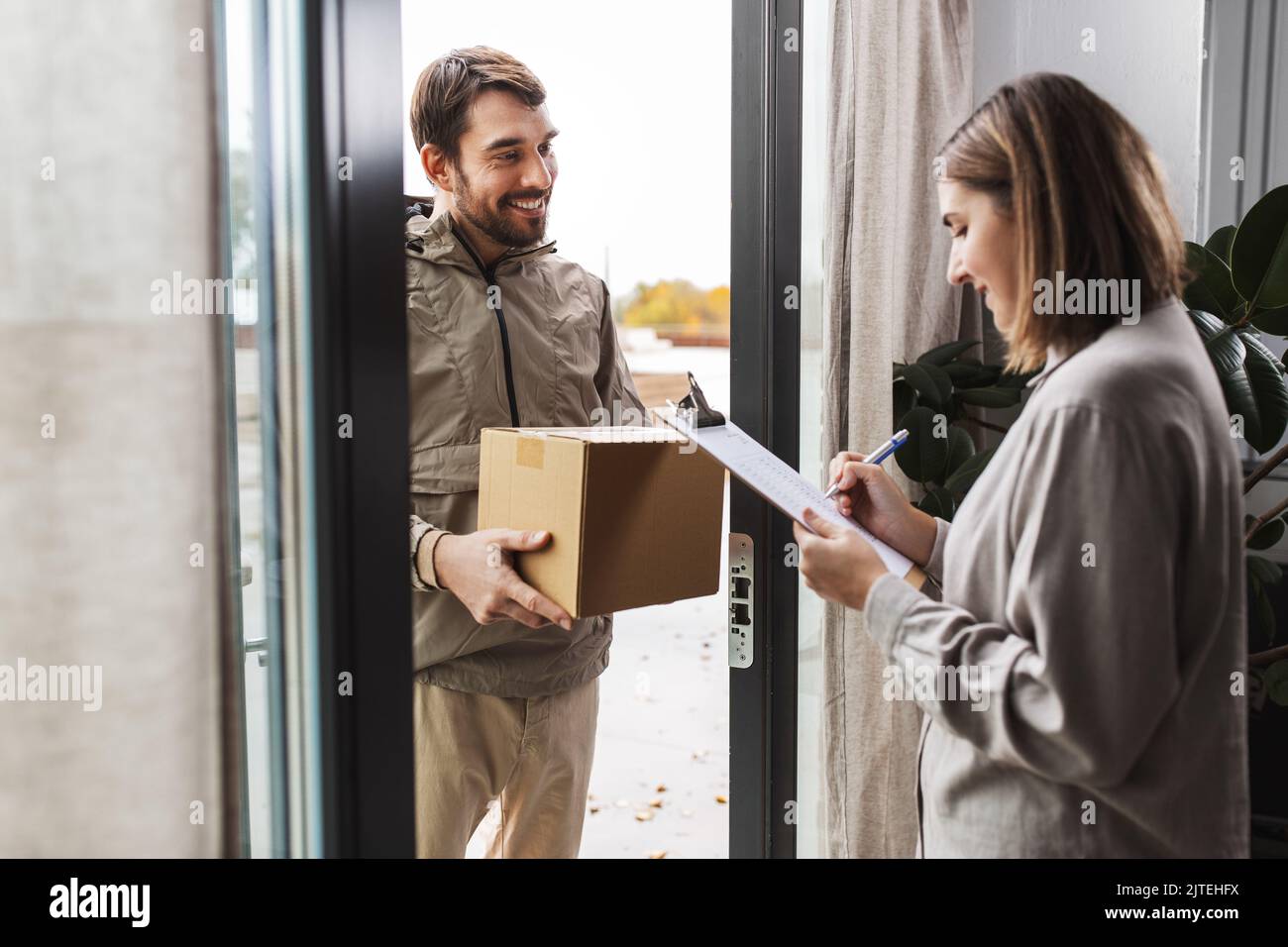 delivery man with parcel box and customer at home Stock Photo - Alamy