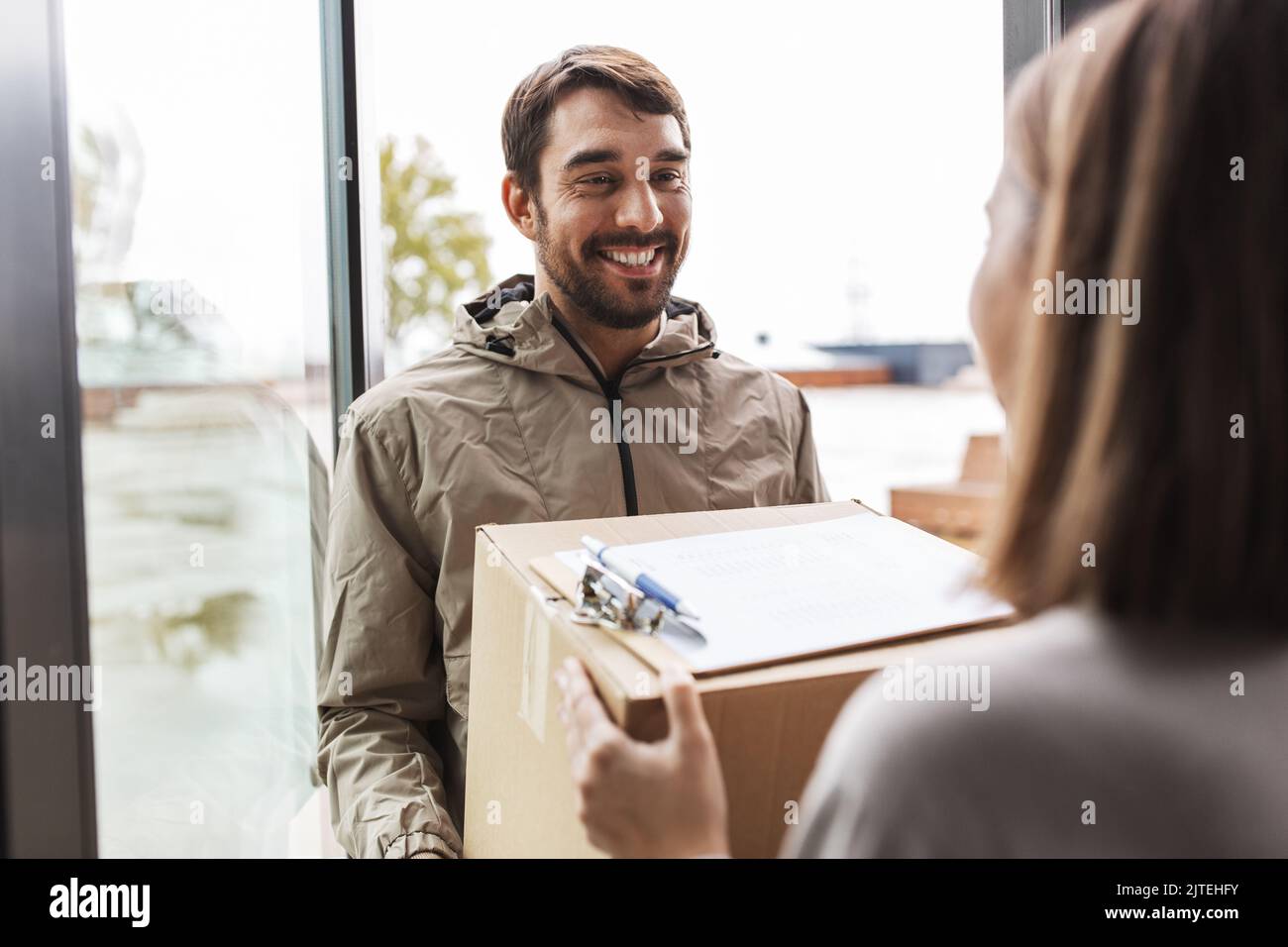 delivery man with parcel box and customer at home Stock Photo - Alamy