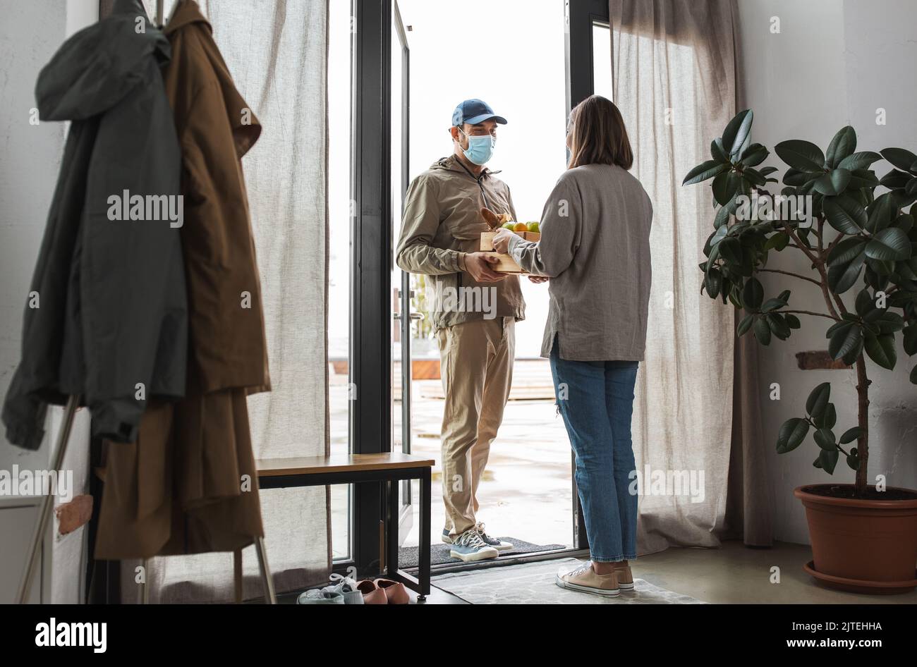 food delivery man in mask giving order to customer Stock Photo - Alamy