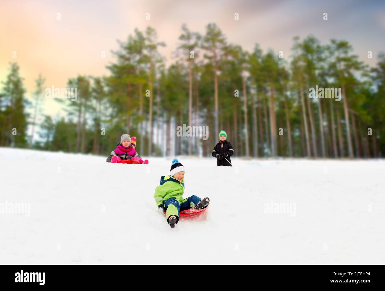 kids sliding on sleds down snow hill in winter Stock Photo - Alamy