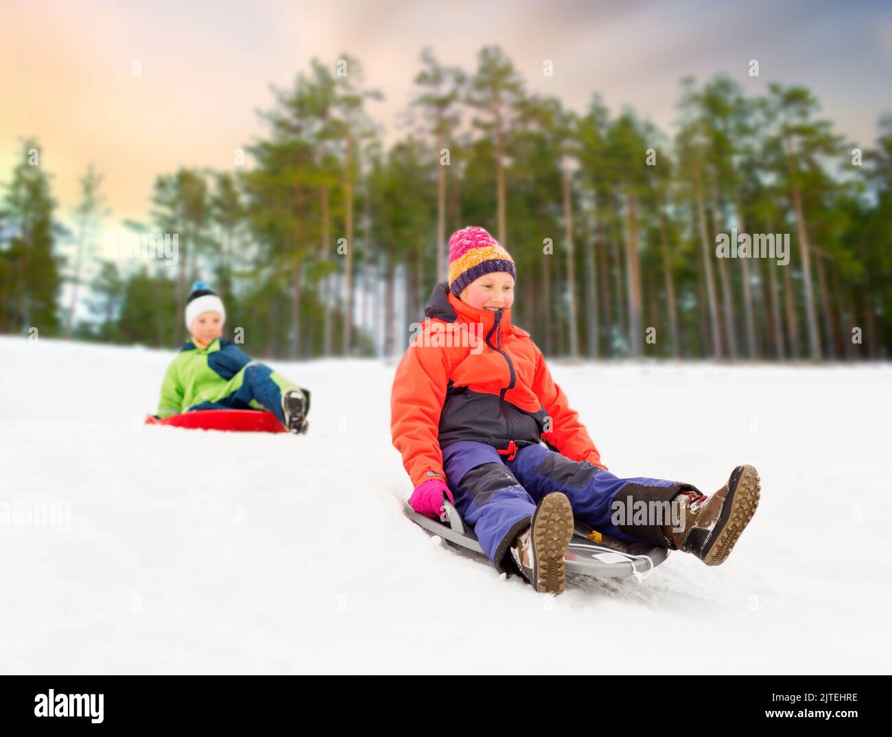 happy kids sliding on sleds down hill in winter Stock Photo - Alamy