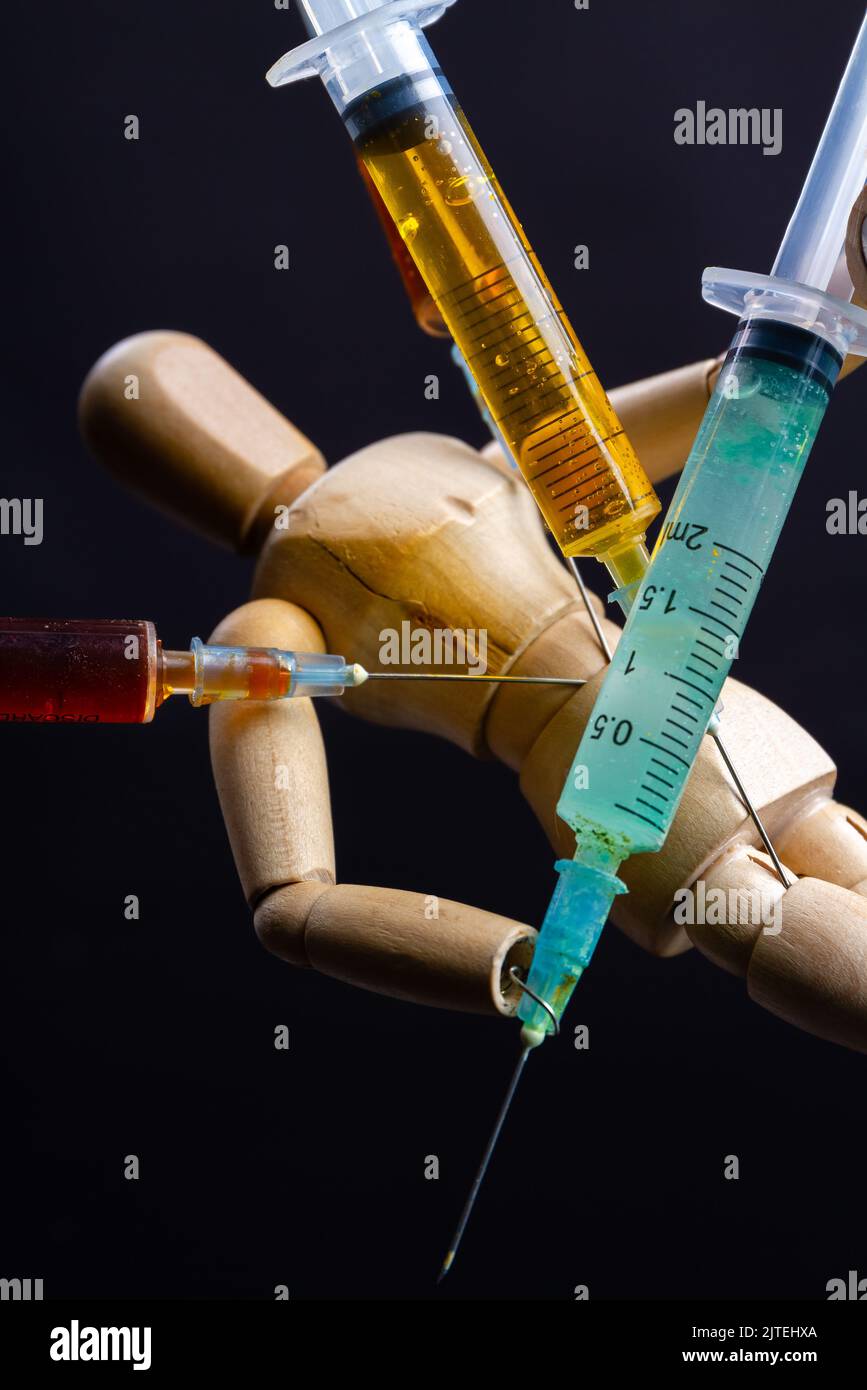 Close-up wooden doll dummy mannequin with stucked syringes. Drug trap ...