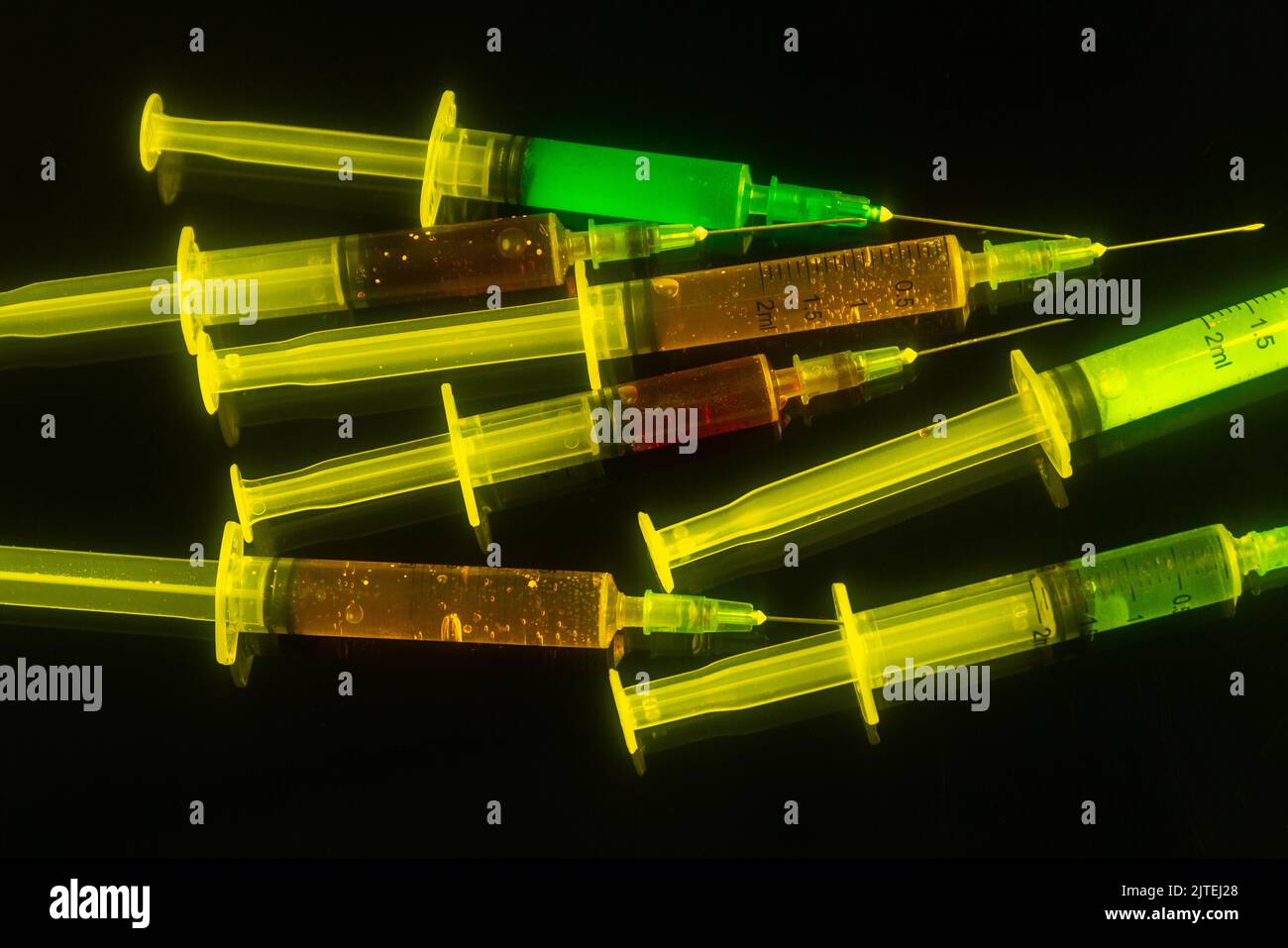 Many syringes with yellow lighting isolated on black background. Drug ...