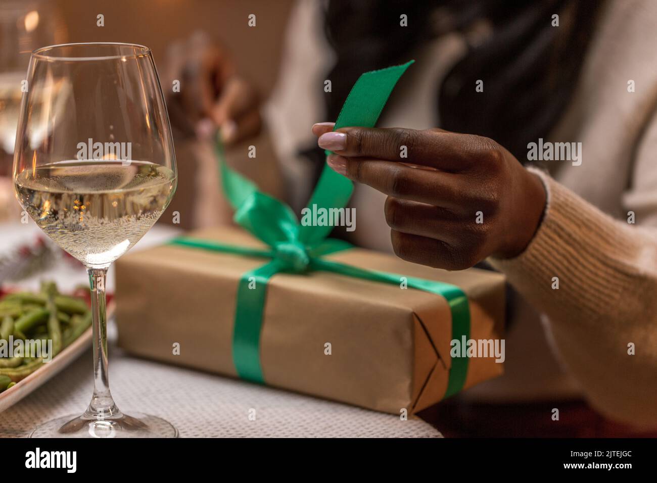 woman opening christmas gift at dinner party Stock Photo - Alamy