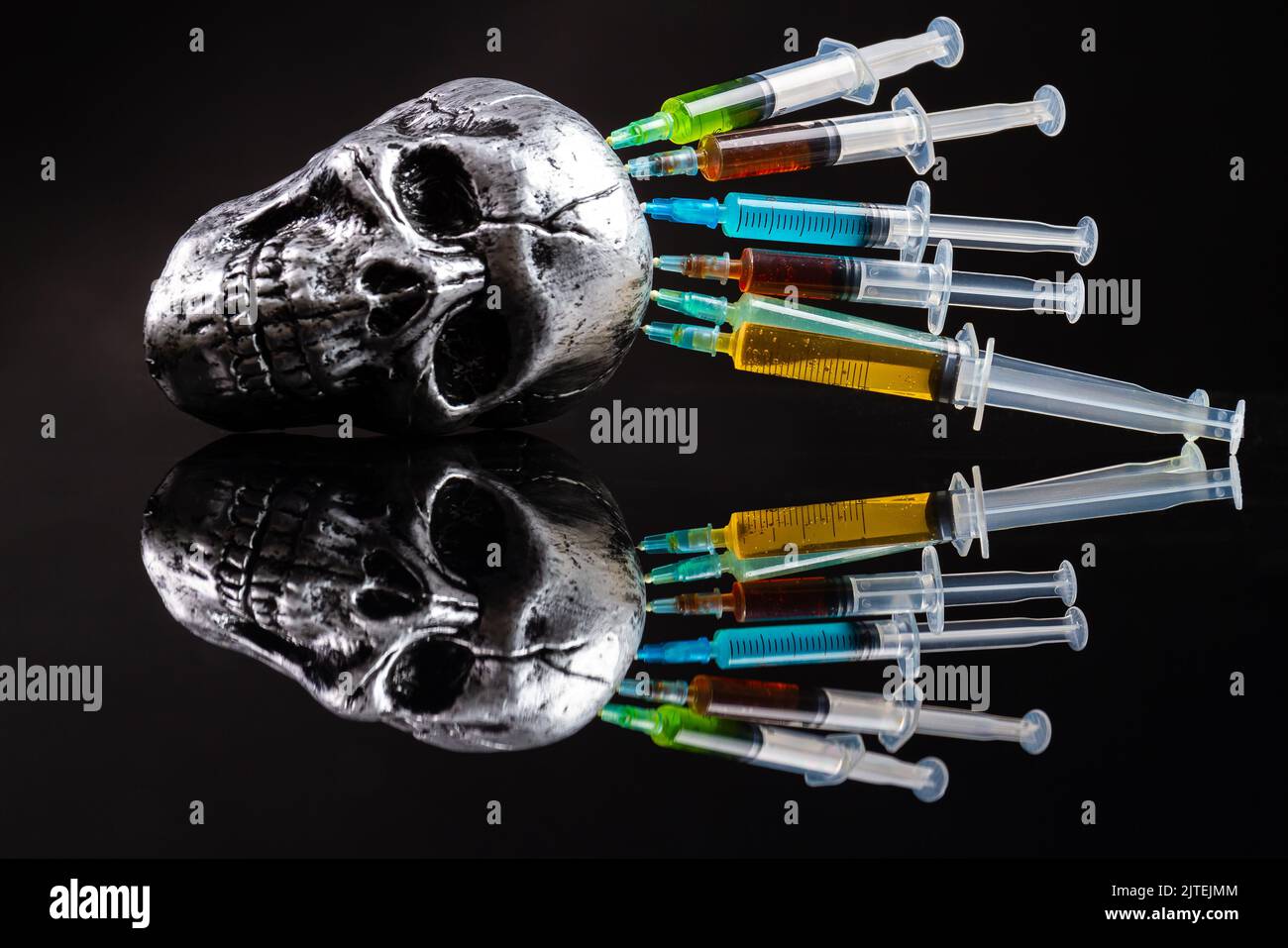 Metallic humans skull with colorful stucked syringes on black ...