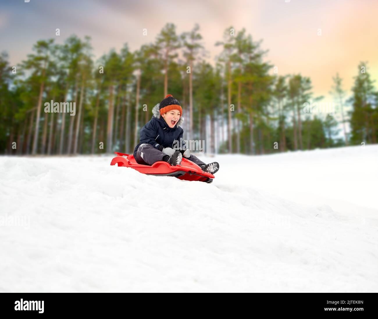happy boy sliding on sled down snow hill in winter Stock Photo - Alamy