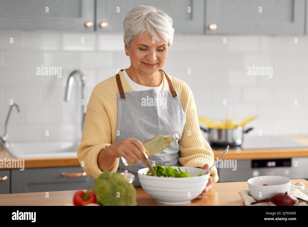 happy woman adding cooking oil to salad on kitchen Stock Photo - Alamy