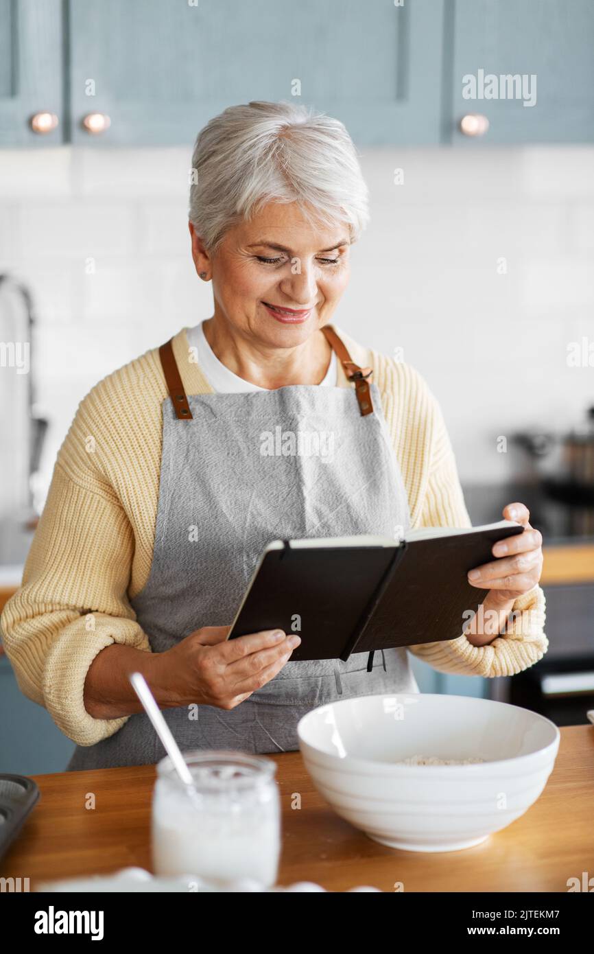 happy woman with cook book cooking food on kitchen Stock Photo - Alamy