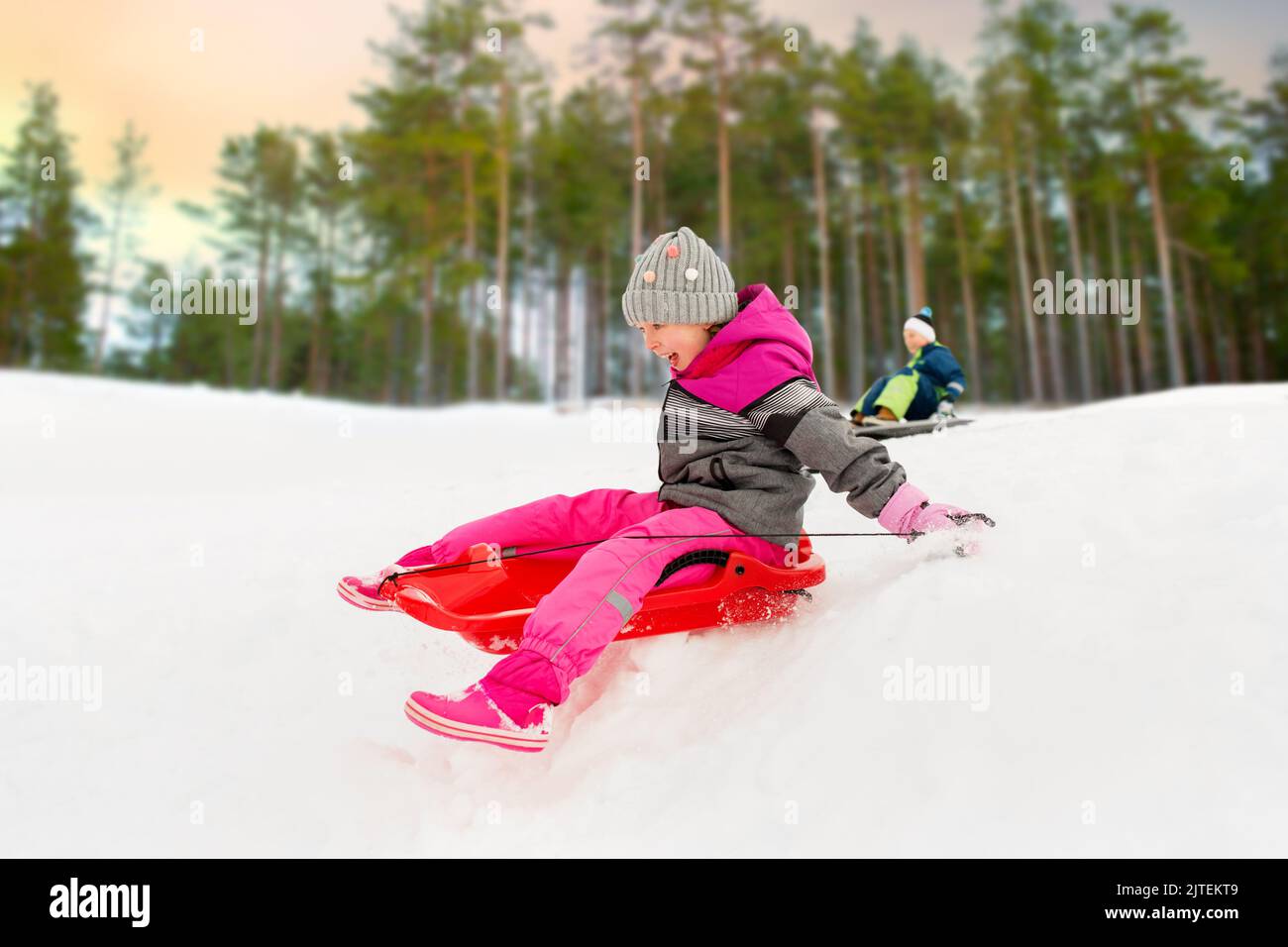 happy little girl sliding down on sled in winter Stock Photo - Alamy
