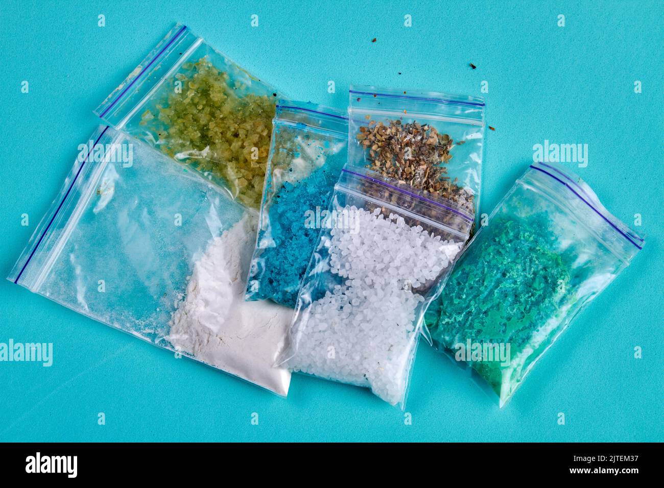Plastic packets with various different colorful drugs. Isolated on blue ...