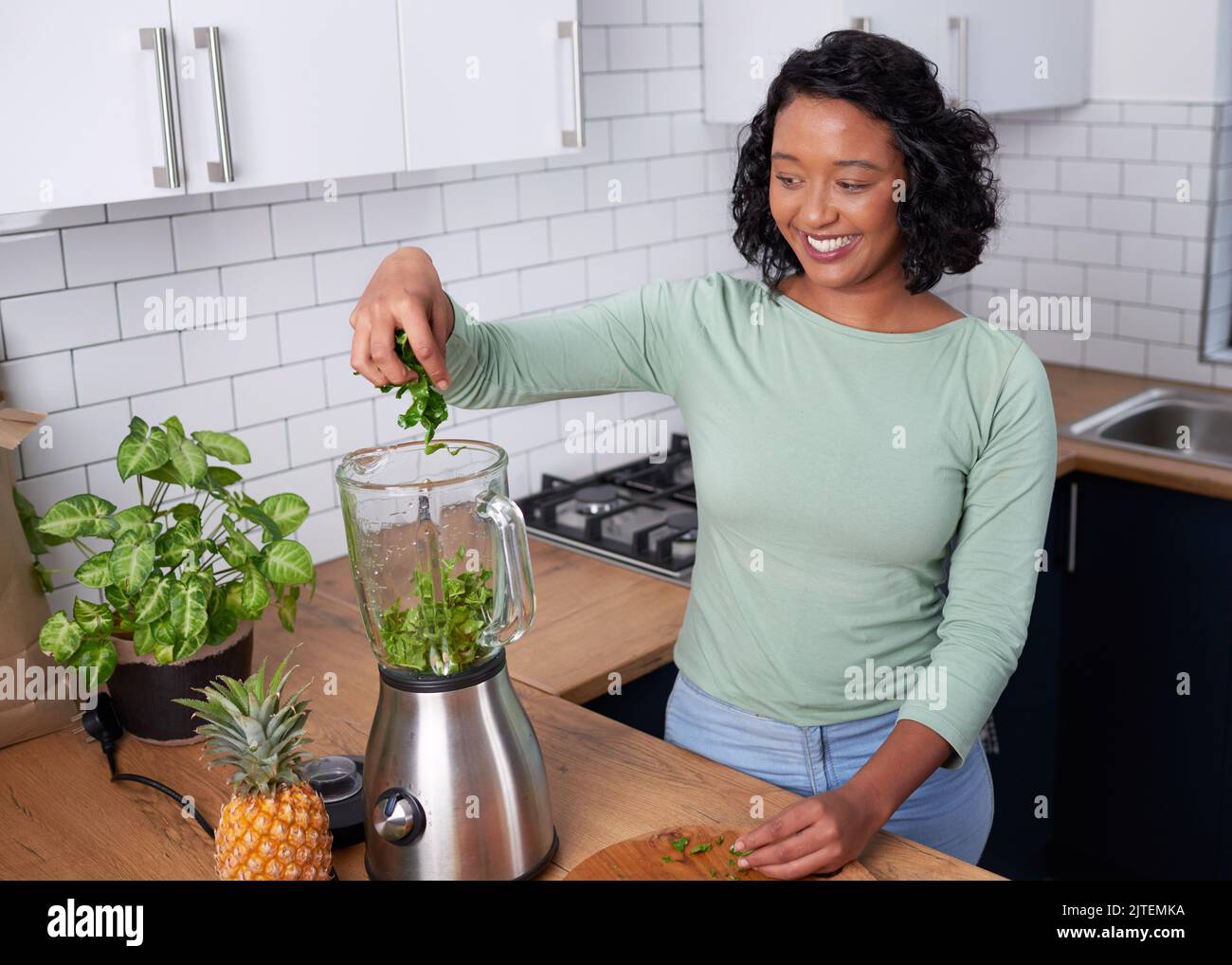 A Young Multi Ethnic Woman Puts Chopped Spinach Into A Blender To Make