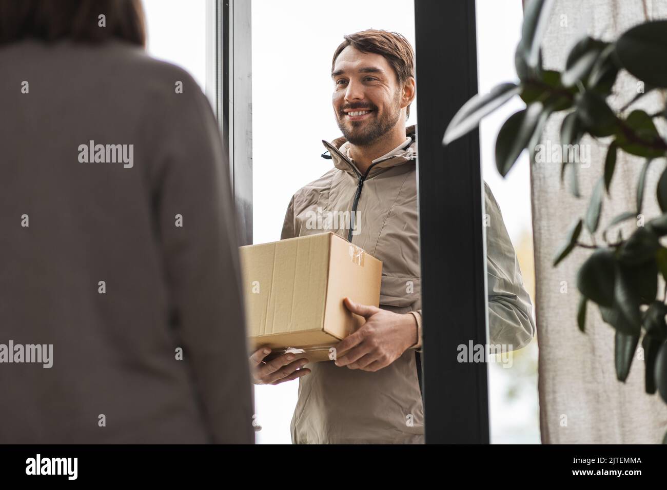 delivery man with parcel box and customer at home Stock Photo - Alamy