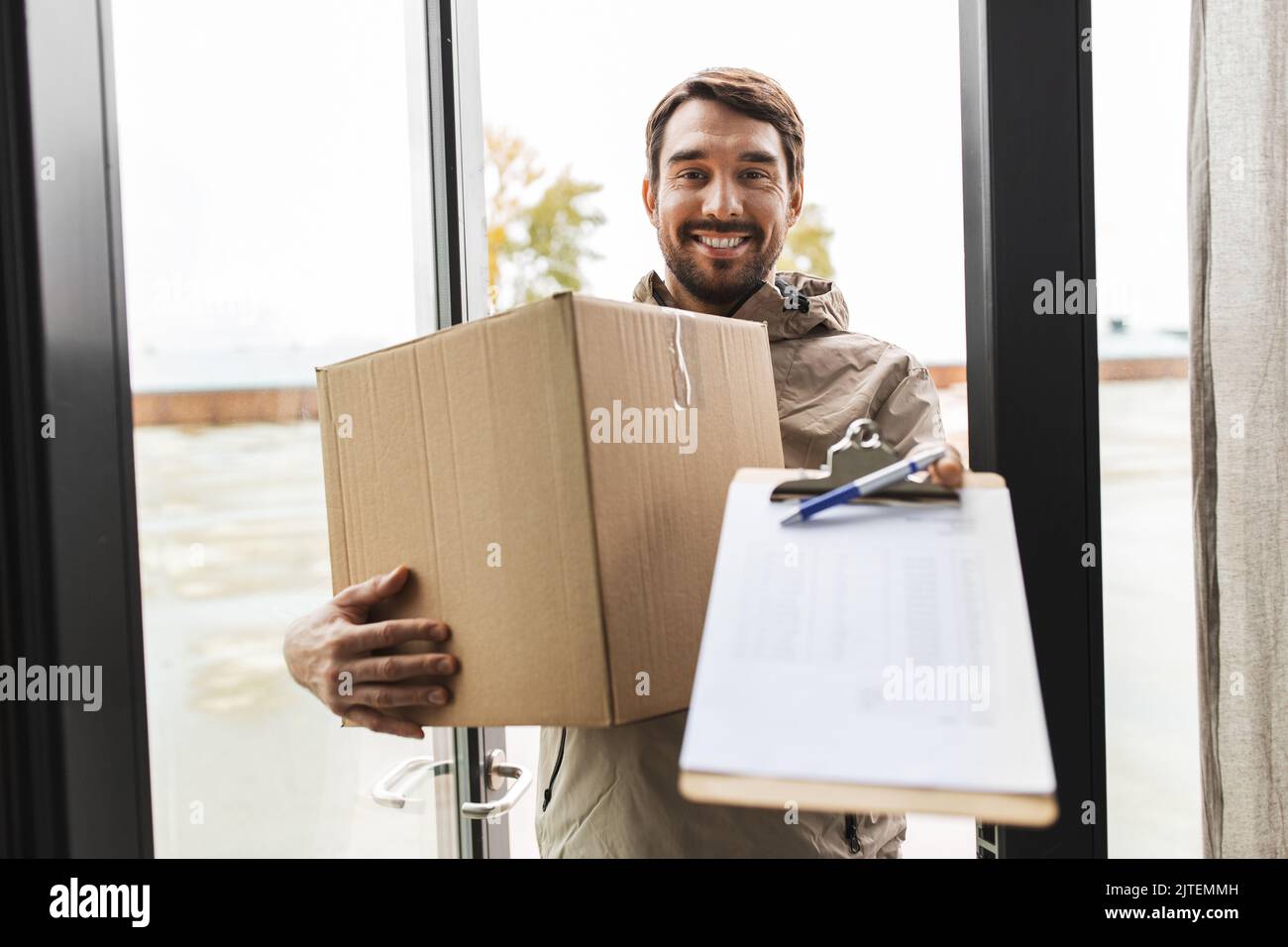 smiling delivery man with parcel box at open door Stock Photo - Alamy