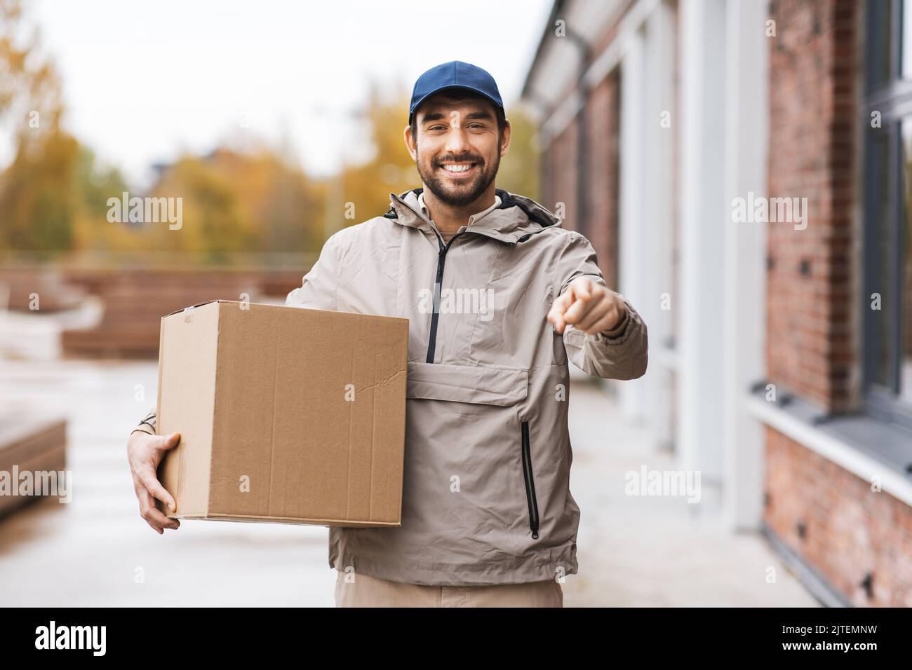 delivery man with parcel box pointing to camera Stock Photo - Alamy
