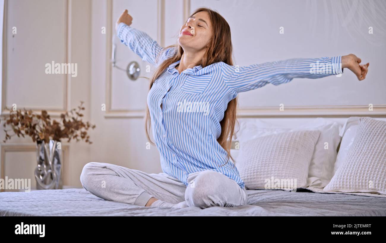 A young female stretching after waking up on the bed Stock Photo - Alamy
