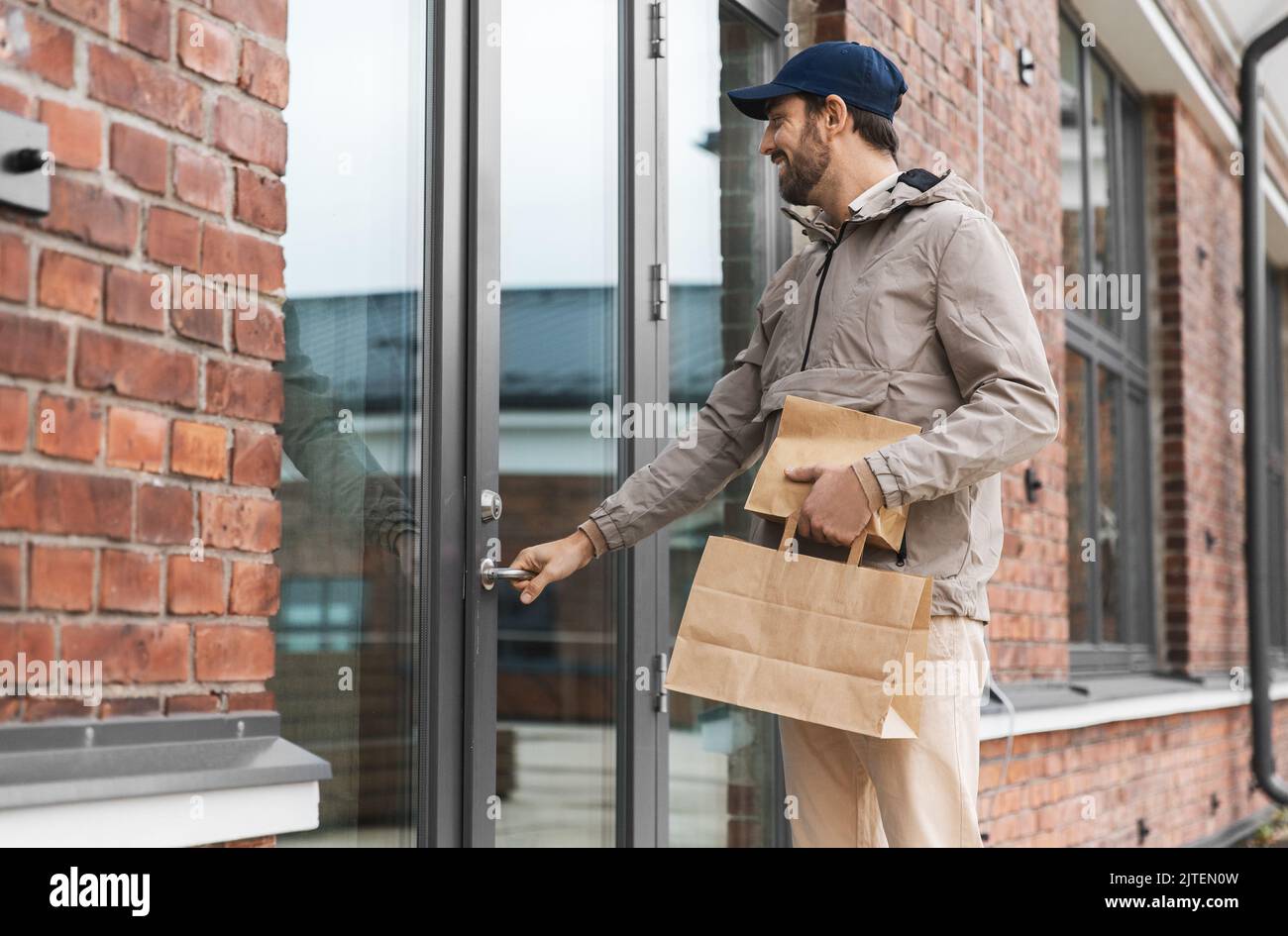 happy food delivery man with paper bags at door Stock Photo - Alamy