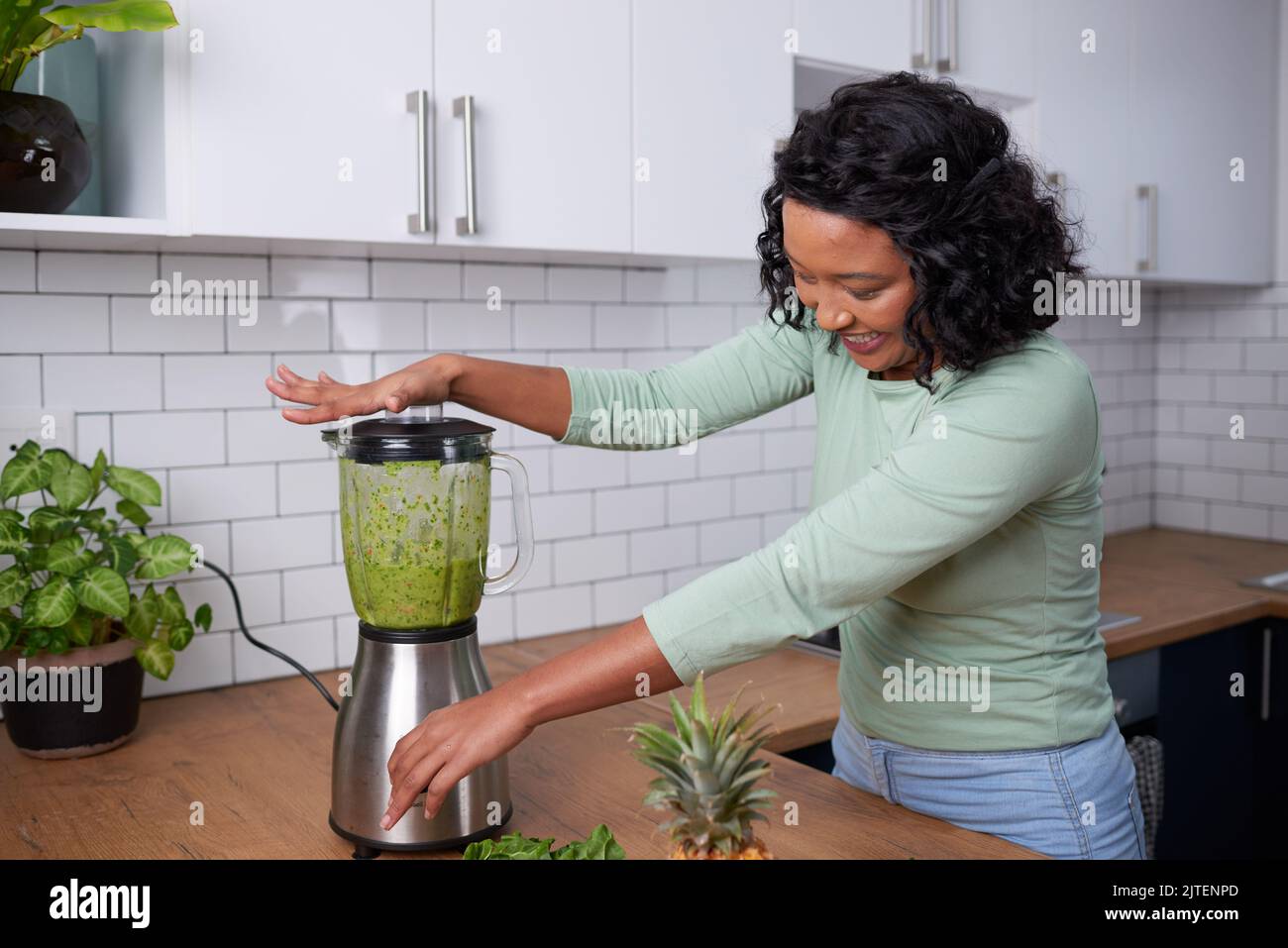 A young multi-ethnic woman blends a smoothie on kitchen counter Stock ...