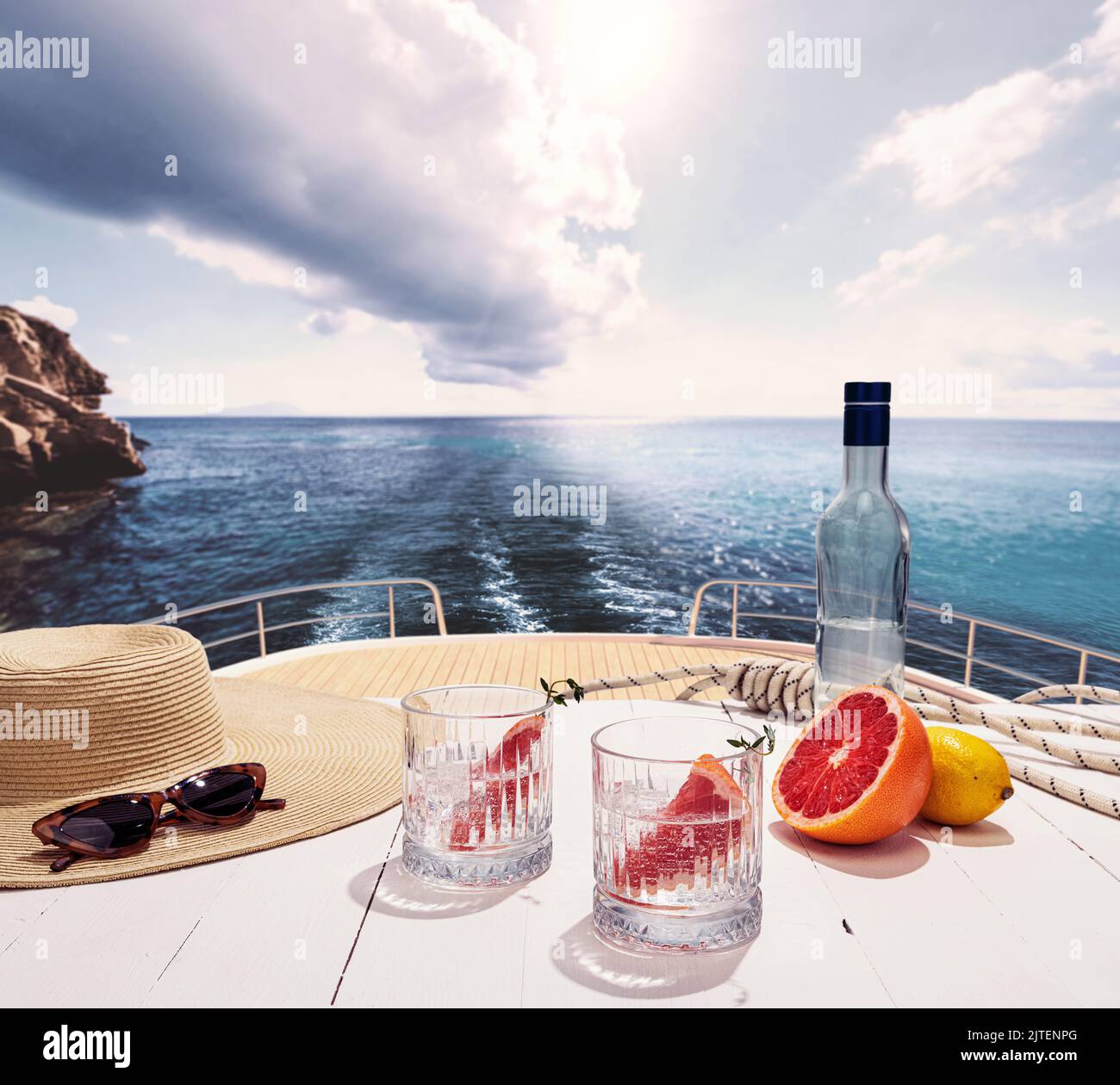 Bottle of pure water and two glasses and ripe grapefruit on deck of ...