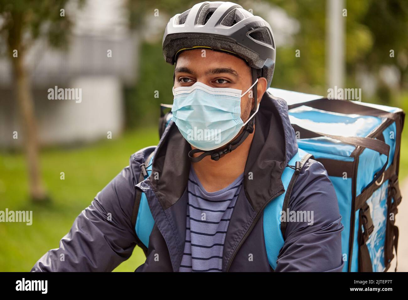 food delivery man in mask and bicycle helmet Stock Photo - Alamy