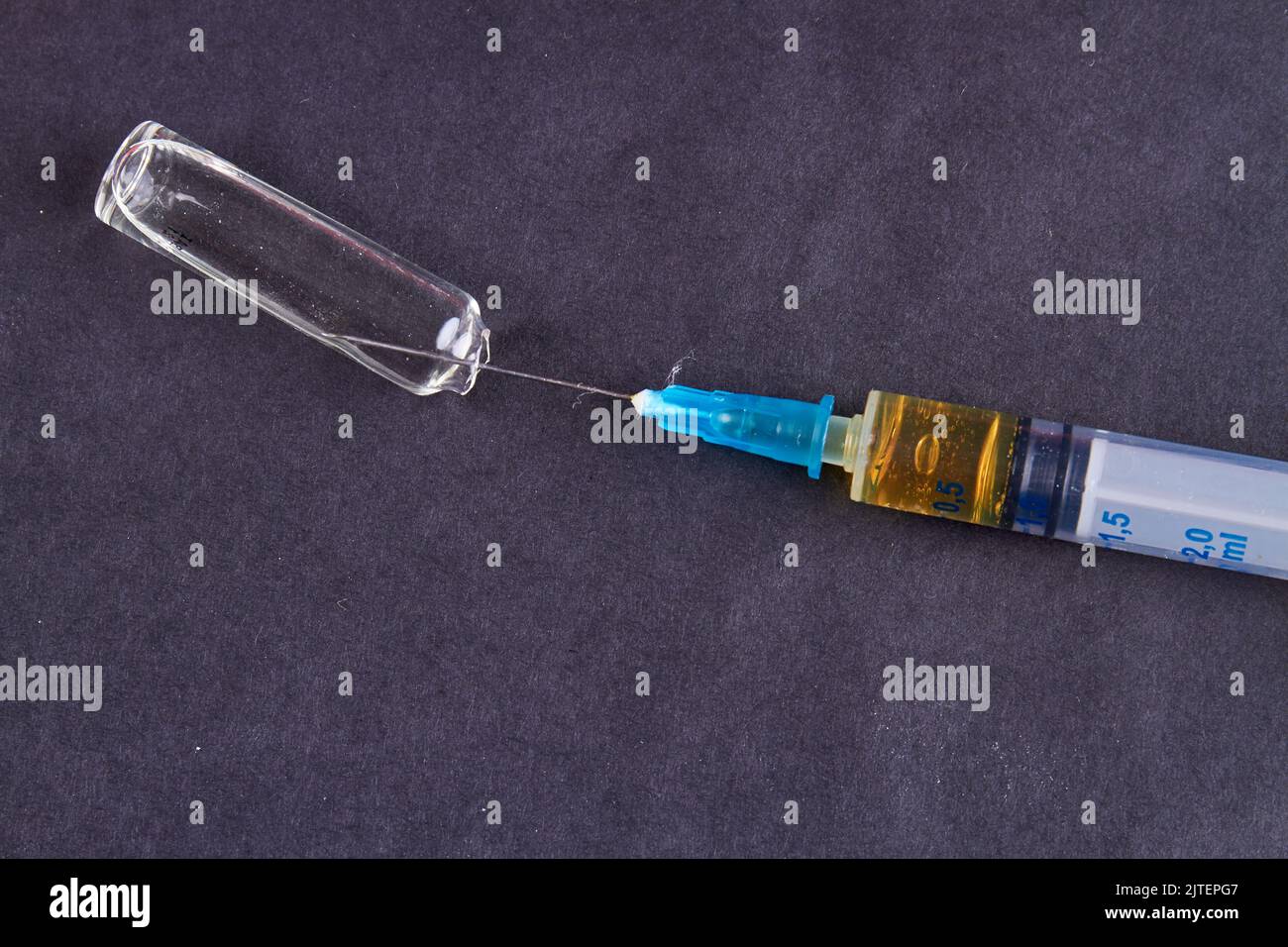 Close-up syringe with glass ampulla on black background. Drug use or ...