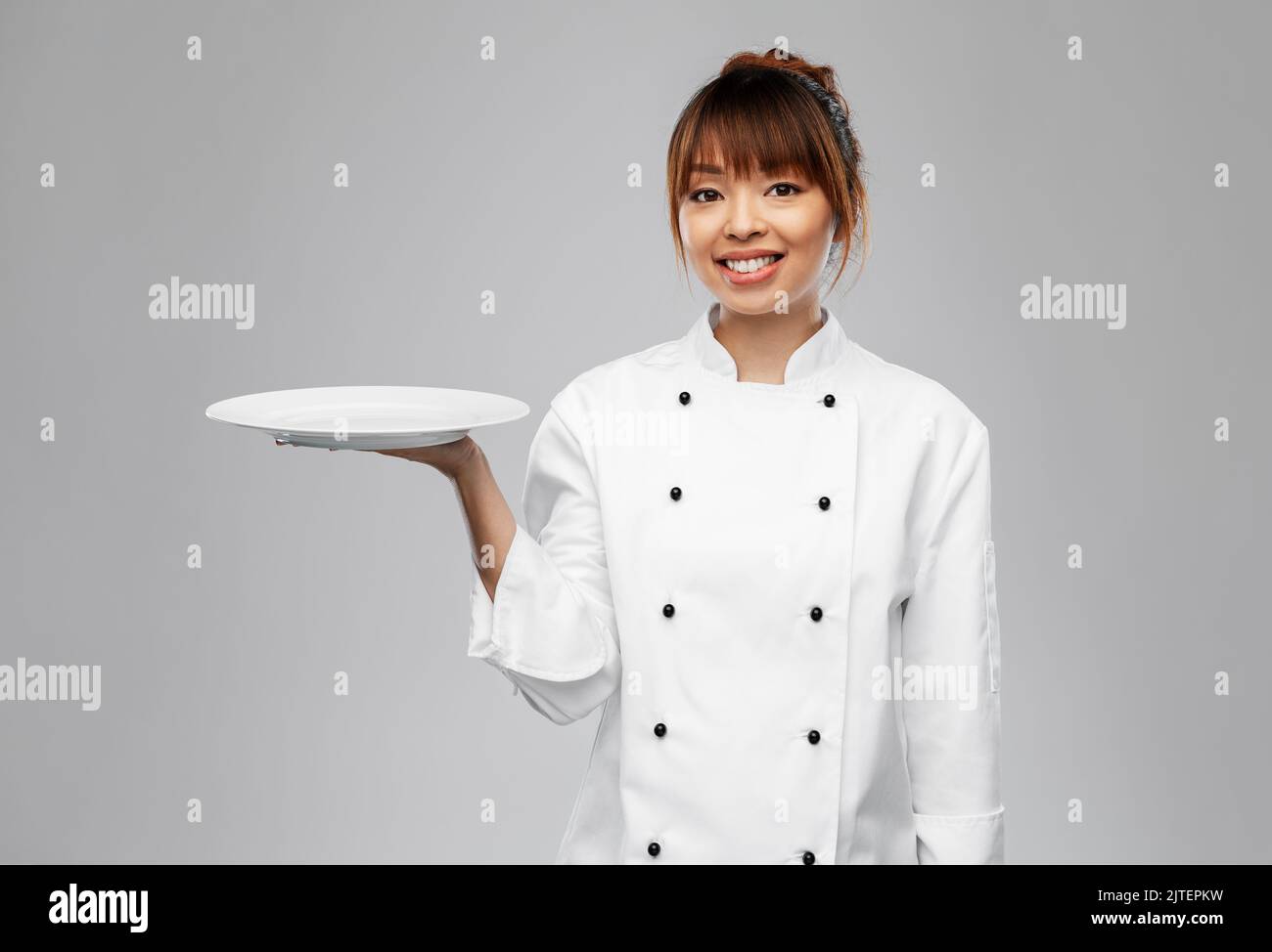 happy smiling female chef holding empty plate Stock Photo - Alamy