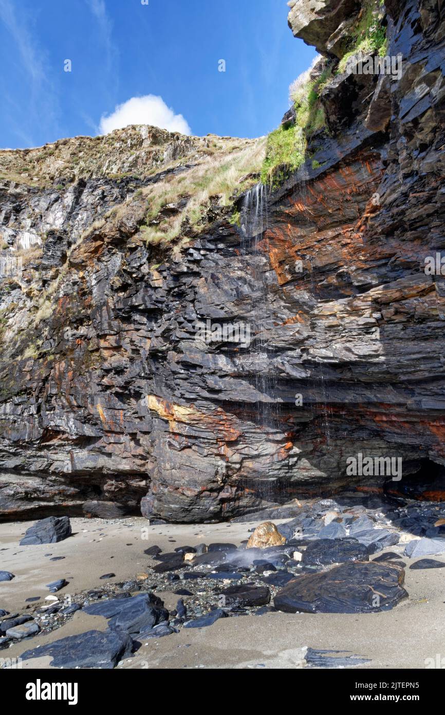 Small waterfall flowing down a cliff face, Tregardock Beach, near ...