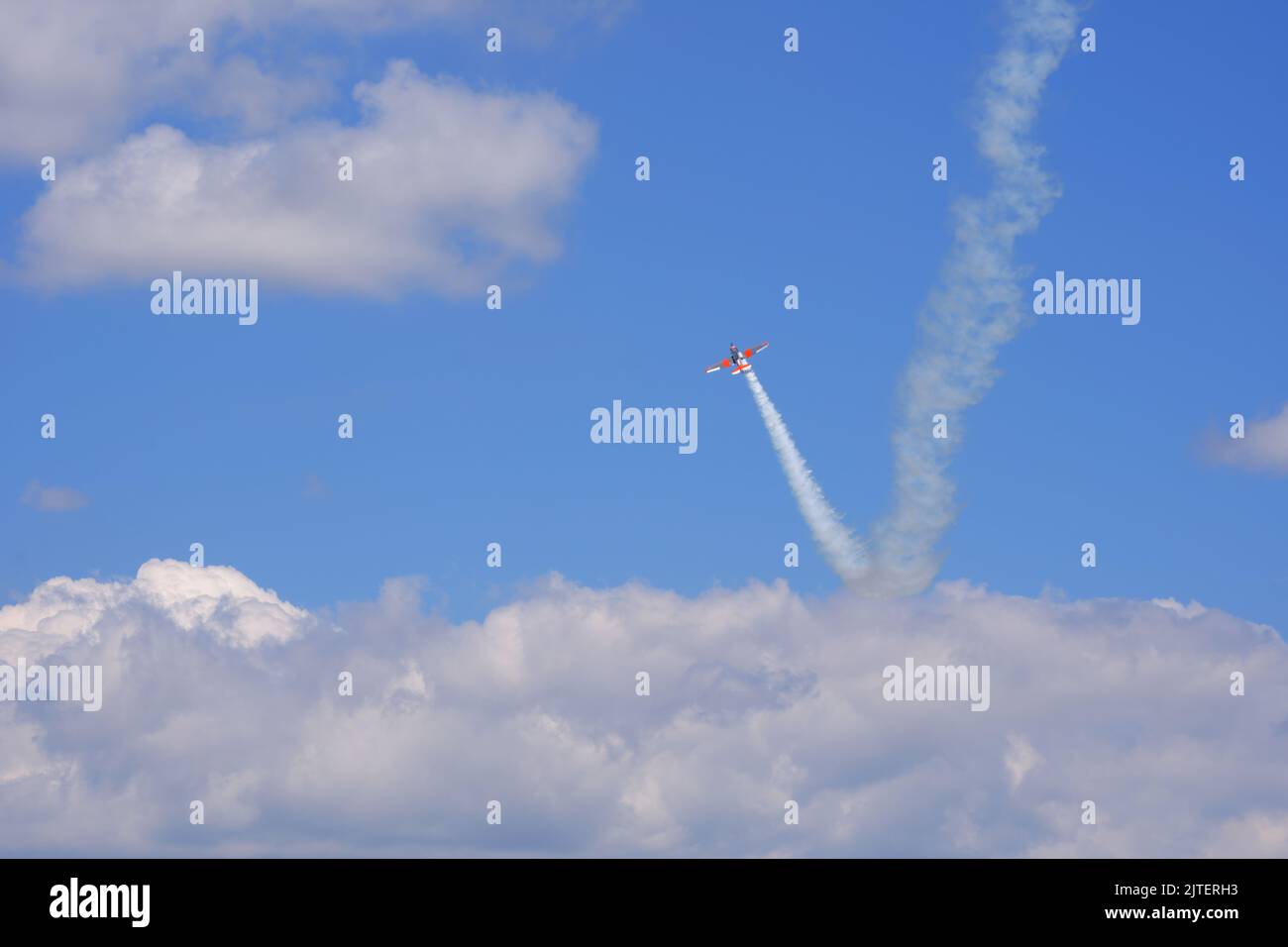 Single engine small airplane making acrobatic maneuvers at cloudy sky ...