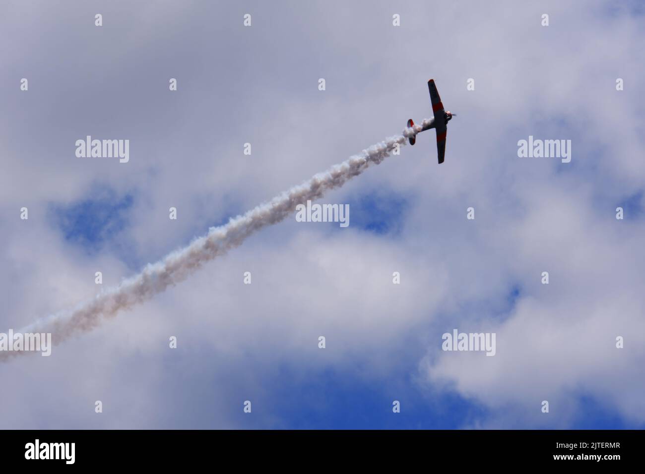 Single engine small airplane making acrobatic maneuvers at cloudy sky ...