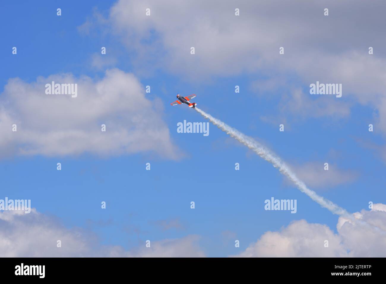 Single Engine Small Airplane Making Acrobatic Maneuvers At Cloudy Sky With Smoke On Tail Stock