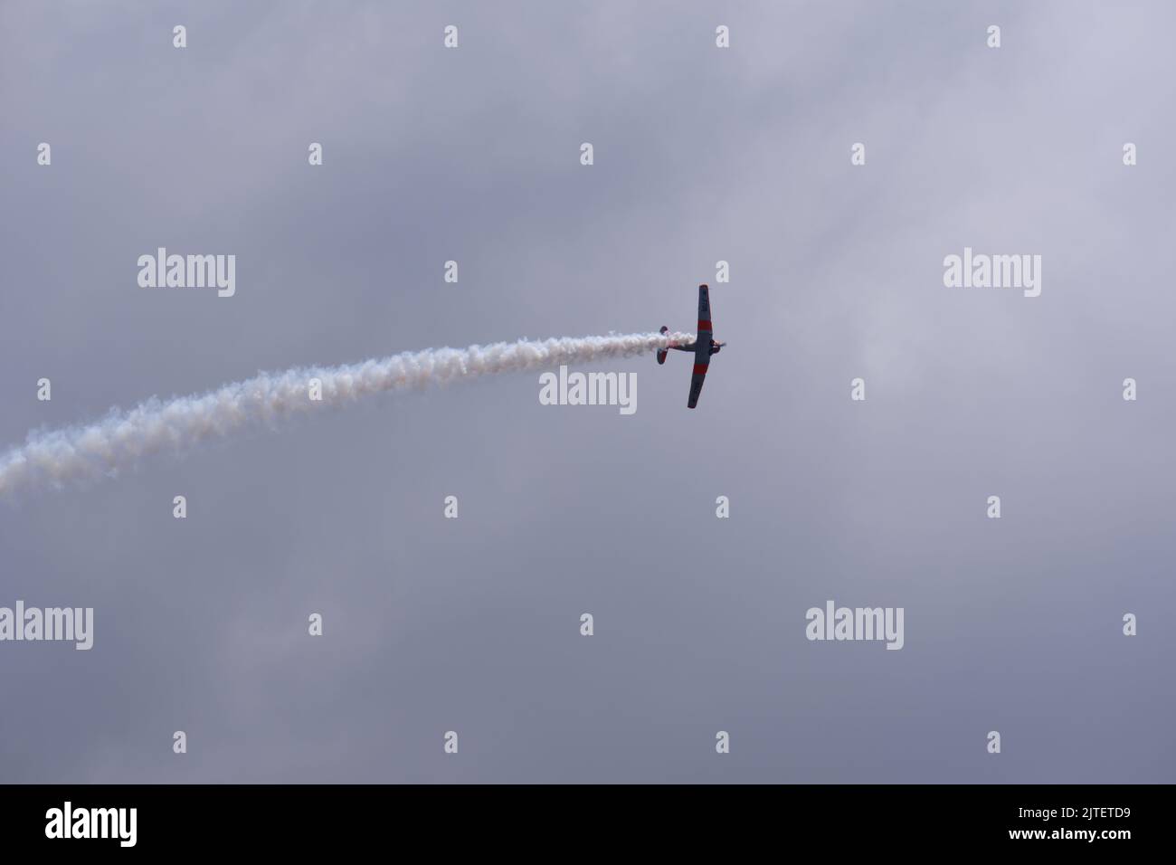 Single engine small airplane making acrobatic maneuvers at cloudy sky ...