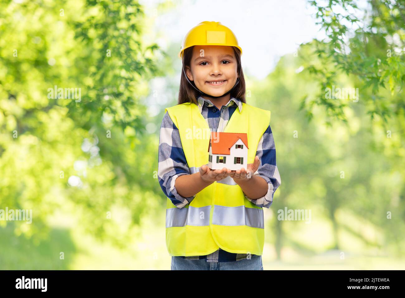 girl in helmet and safety vest holding house Stock Photo - Alamy