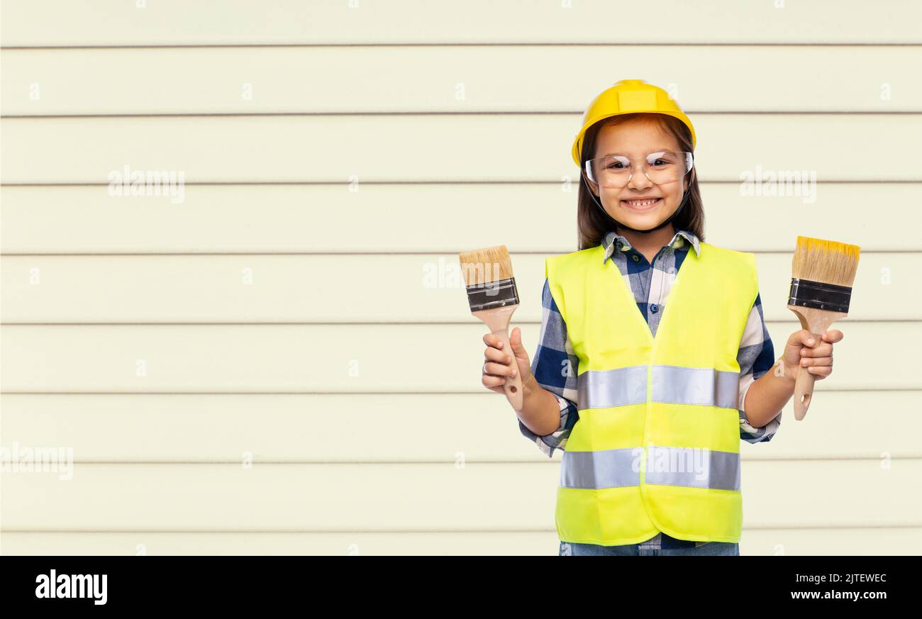 girl in helmet and safety vest with paint brush Stock Photo - Alamy