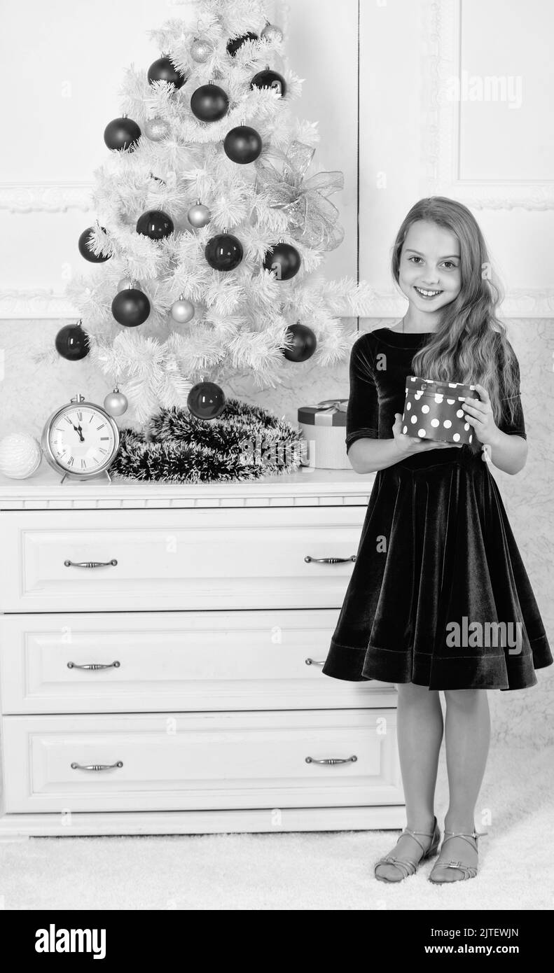 Best for our kids. Kid girl near christmas tree hold gift box. Child ...