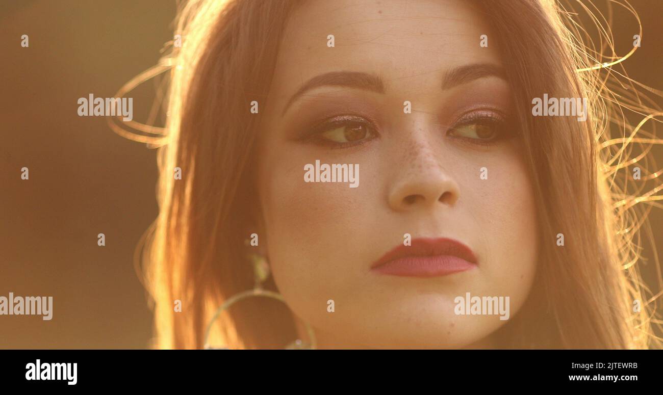 Pensive young woman during dreamlike golden hour sunset time ...