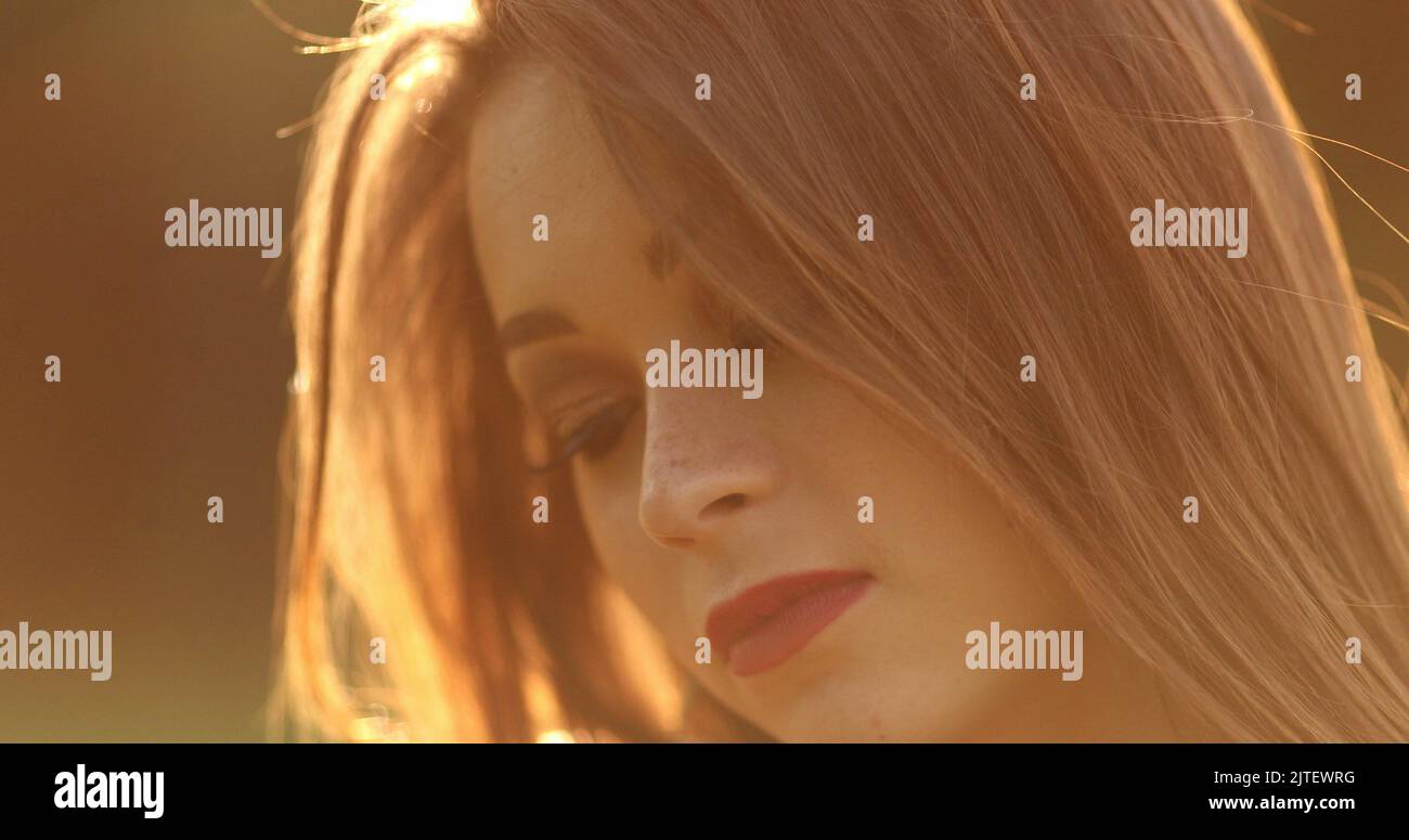 Pensive young woman during dreamlike golden hour sunset time ...