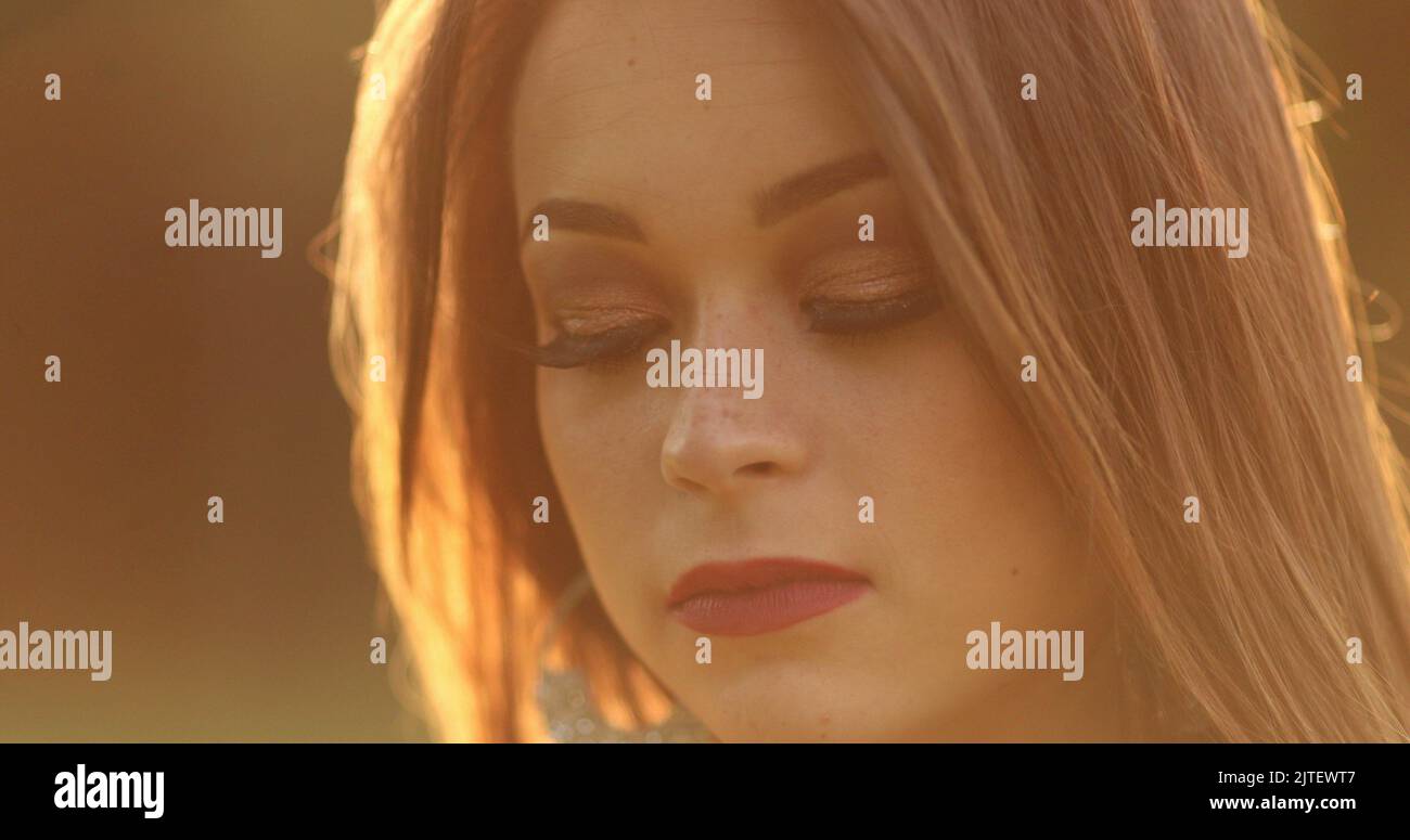 Pensive young woman during dreamlike golden hour sunset time ...